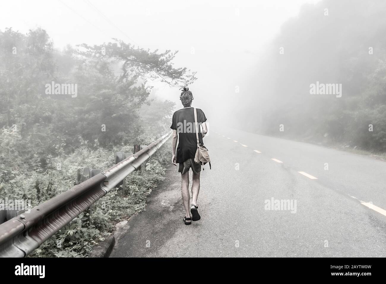 Man walking on the road in fog Stock Photo - Alamy