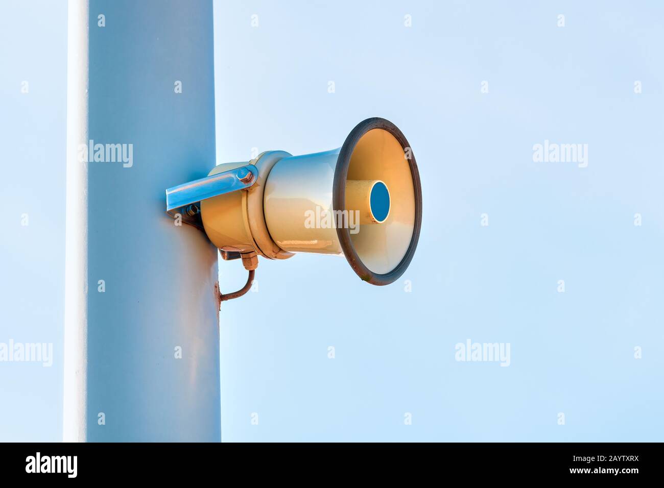 Street loudspeaker megaphone mounted on the post with clear sky as copy ...