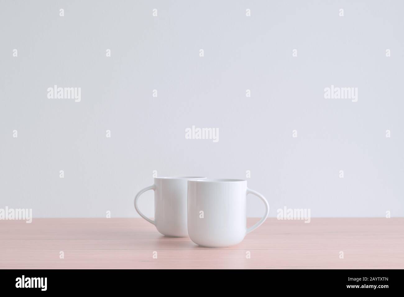 Two white coffee cups on the table in morning with white wall as copy ...