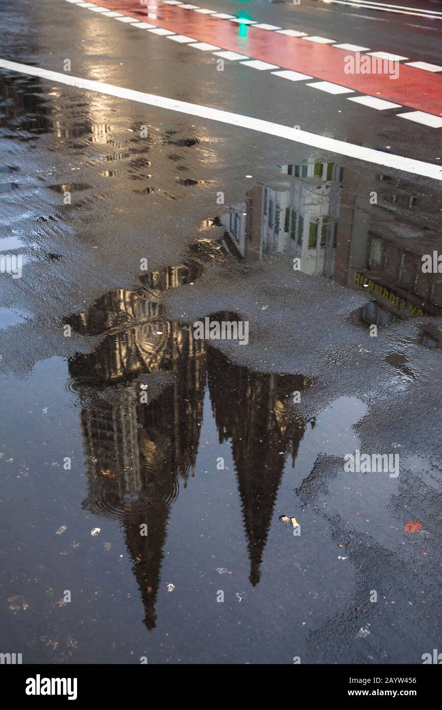 the steeples of the cathedral are reflected in a puddle, Cologne ...