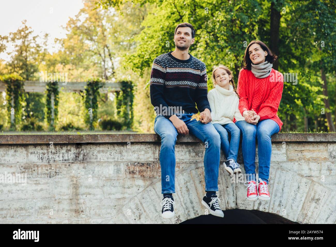 Horizontal portrait of adorable child sits between her mother and ...
