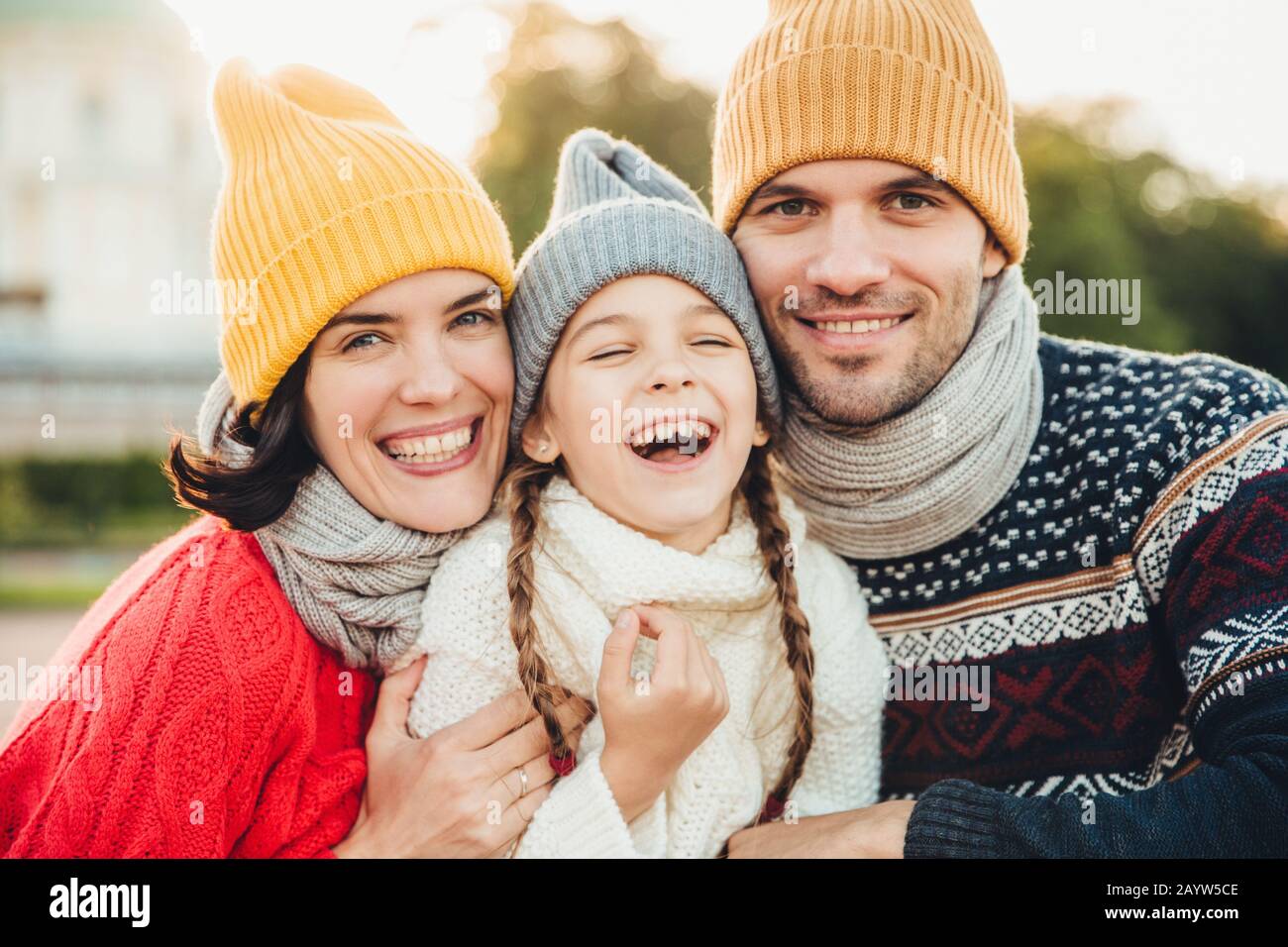 Funny overjoyed small kid laughs as has wonderful time with her parents ...