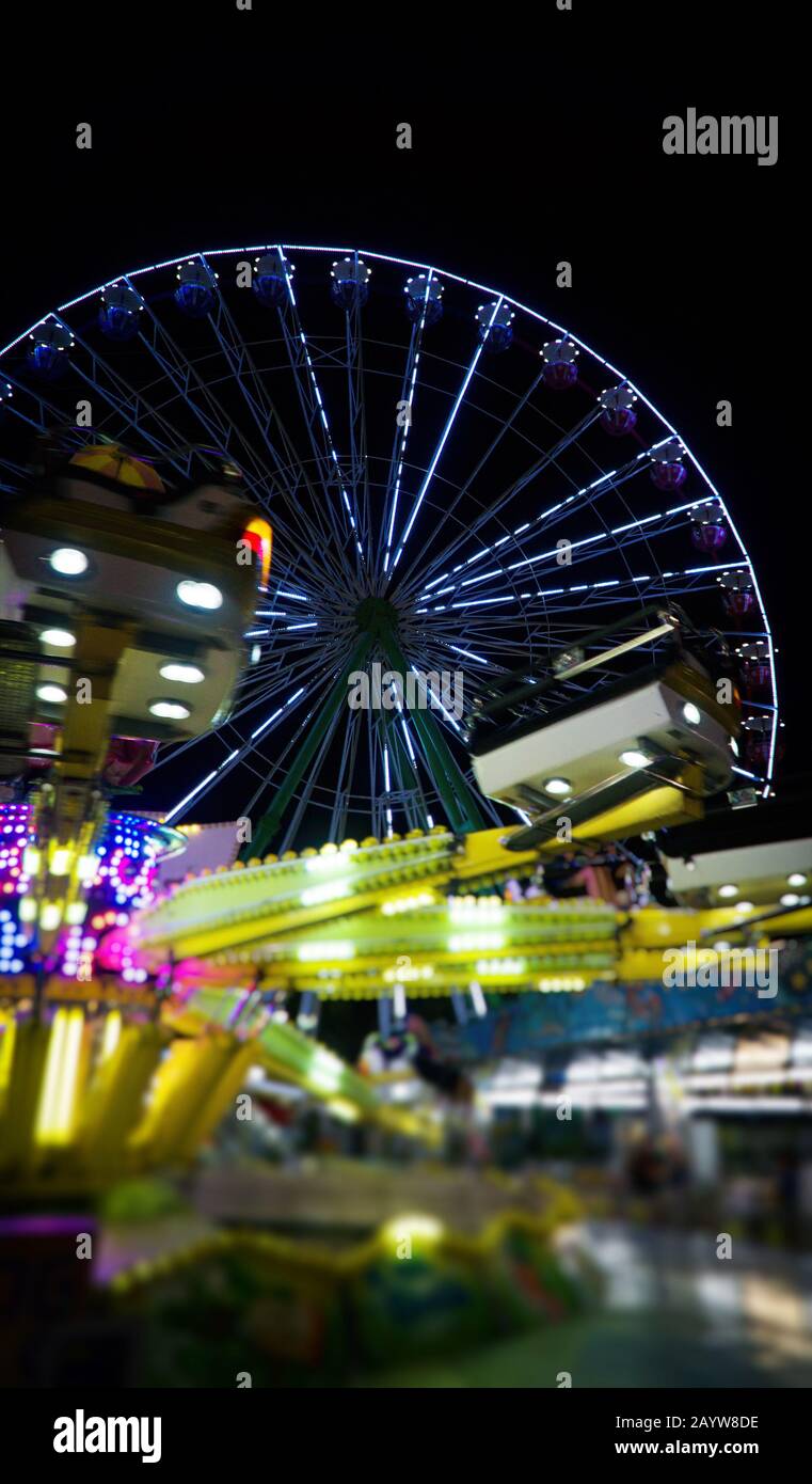 Hurricane ride and ferris wheel in the city amusement park at evening ...