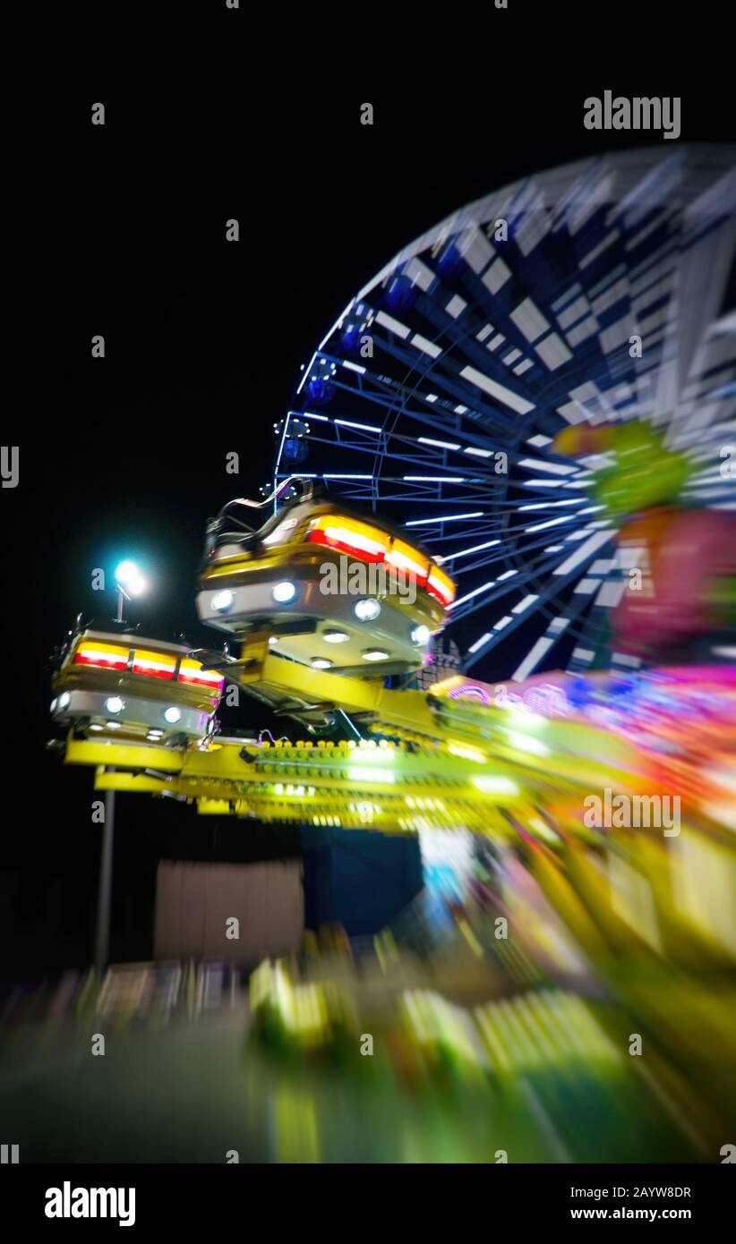 Hurricane ride and ferris wheel in the city amusement park at evening ...