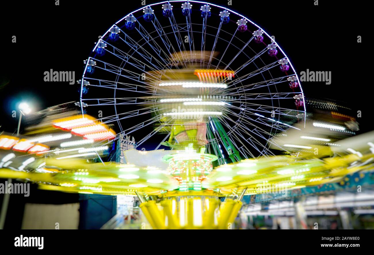 Hurricane ride and ferris wheel in the city amusement park at evening ...