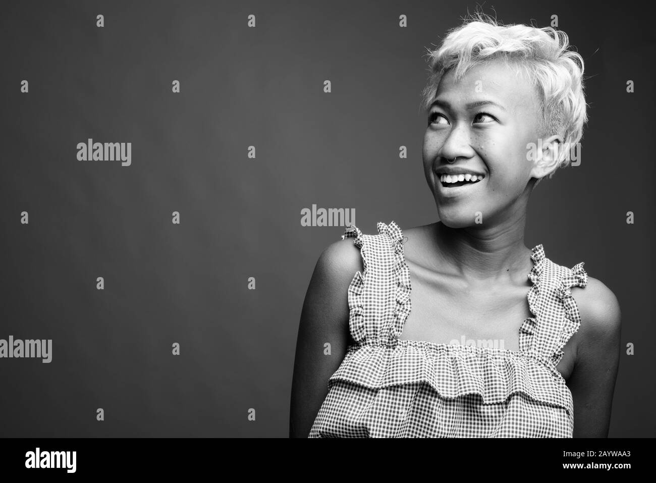 Young beautiful rebellious woman with short hair against gray ...