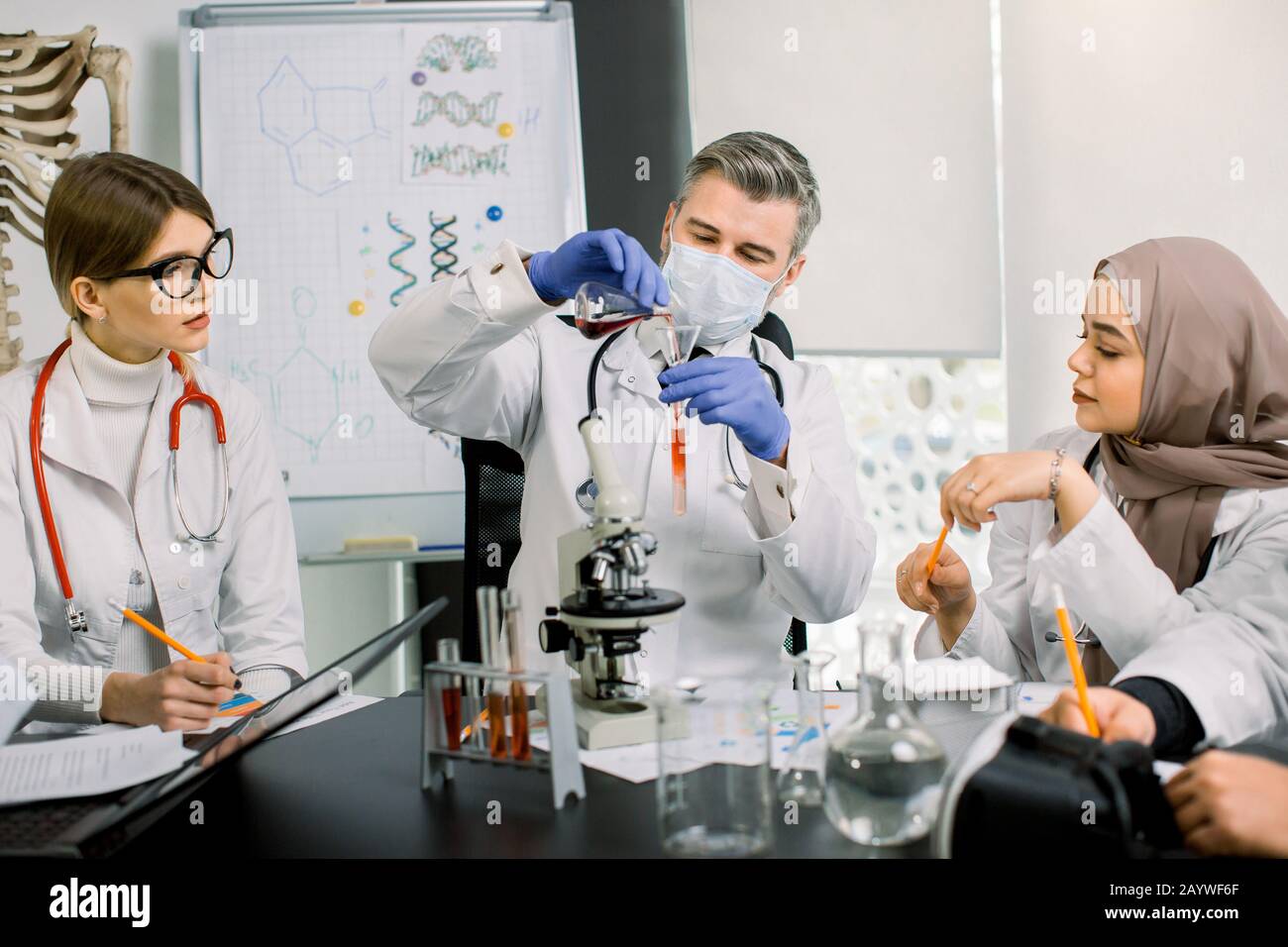 Team of professional scientists, lab workers in uniform testing new ...
