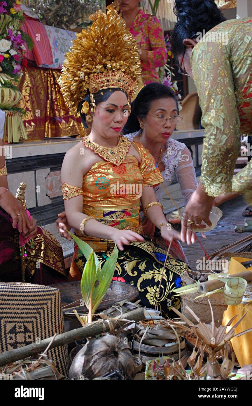 A Balinese bride is guided through a traditional ceremony by other ...