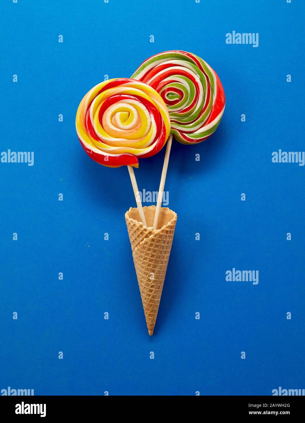 Two colorful spiral lollipops in ice cream cornets over a blue ...