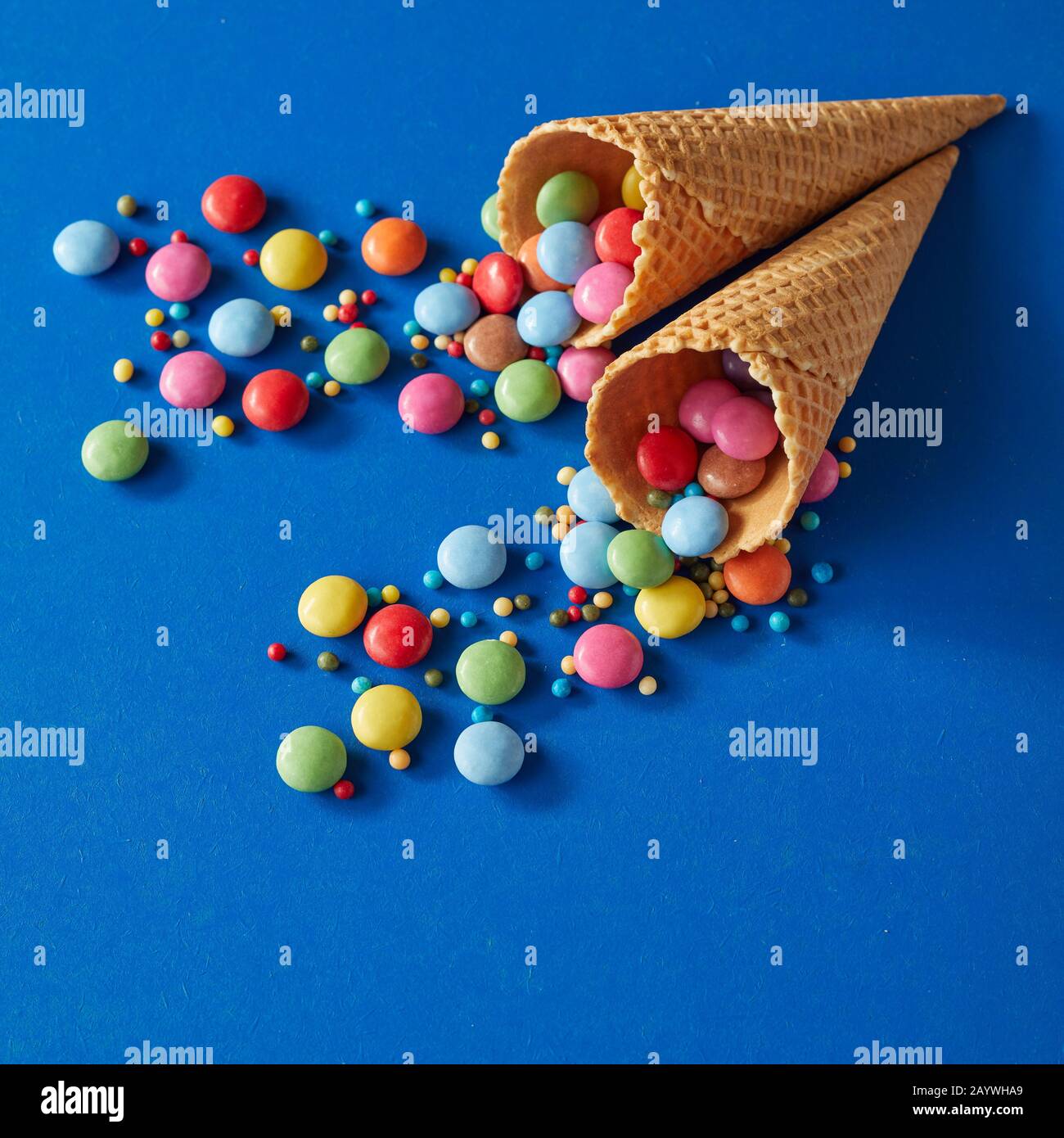 Rainbow colored sugar-coated chocolate candy and sprinkles spilling ...