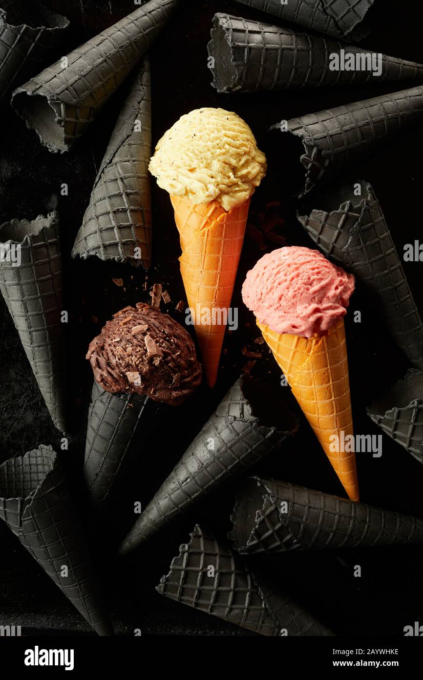 Strawberry, chocolate and vanilla ice cream in wafer cones amongst a ...