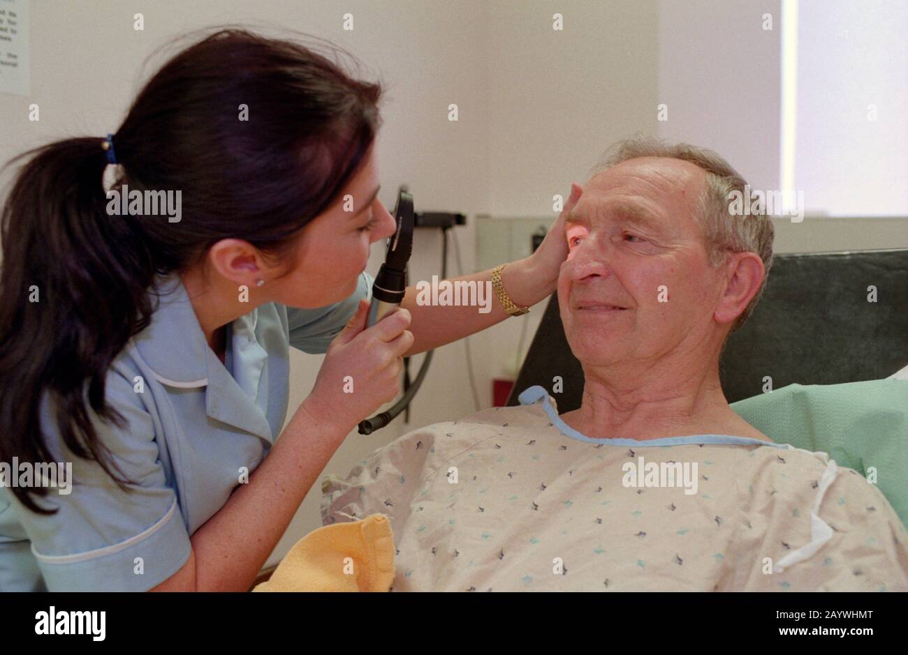 A nurse checking a patients pupil reaction using an opthalmoscope Stock ...