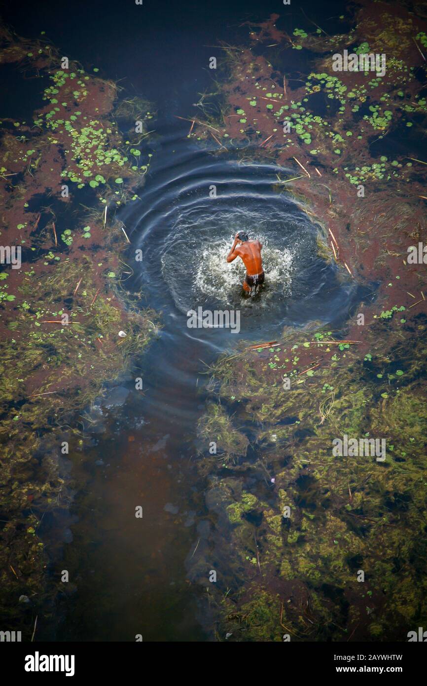 Indianj man bathing in red algae lake Stock Photo - Alamy