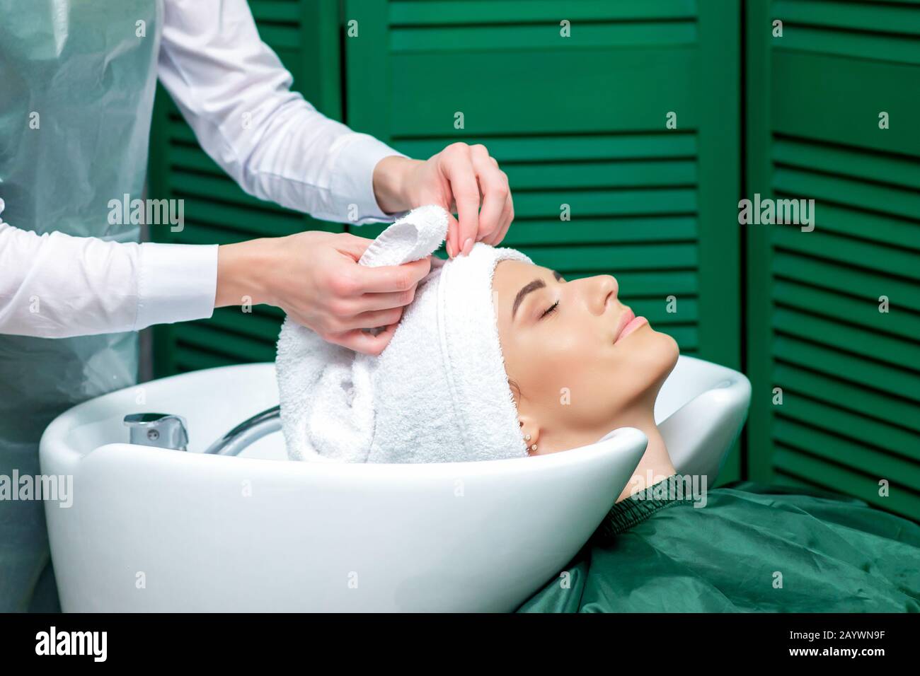 Hairdresser wrapping woman's hair in towel after washing head in the ...