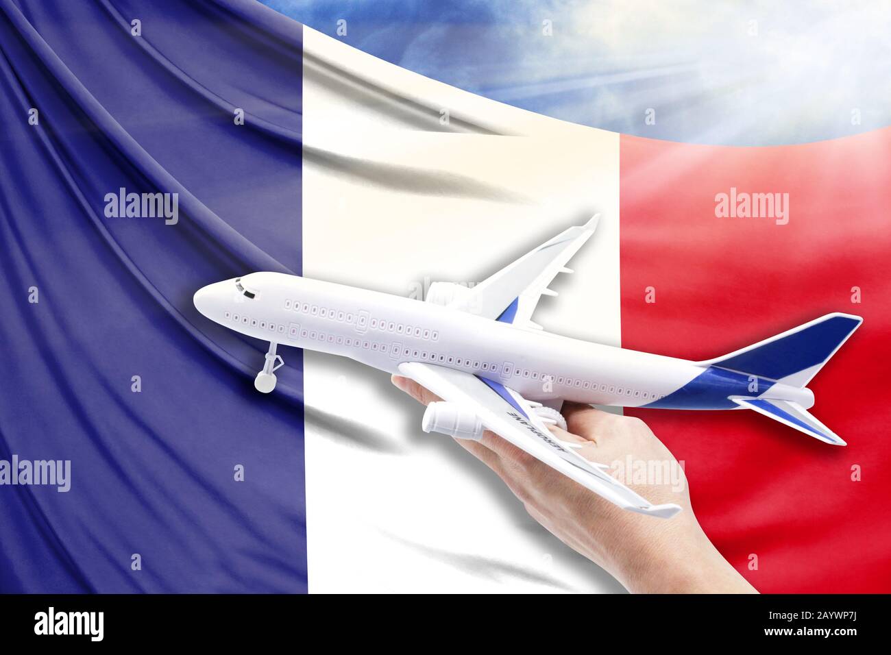 Airplane in hand with national flag of France on a background of blue ...