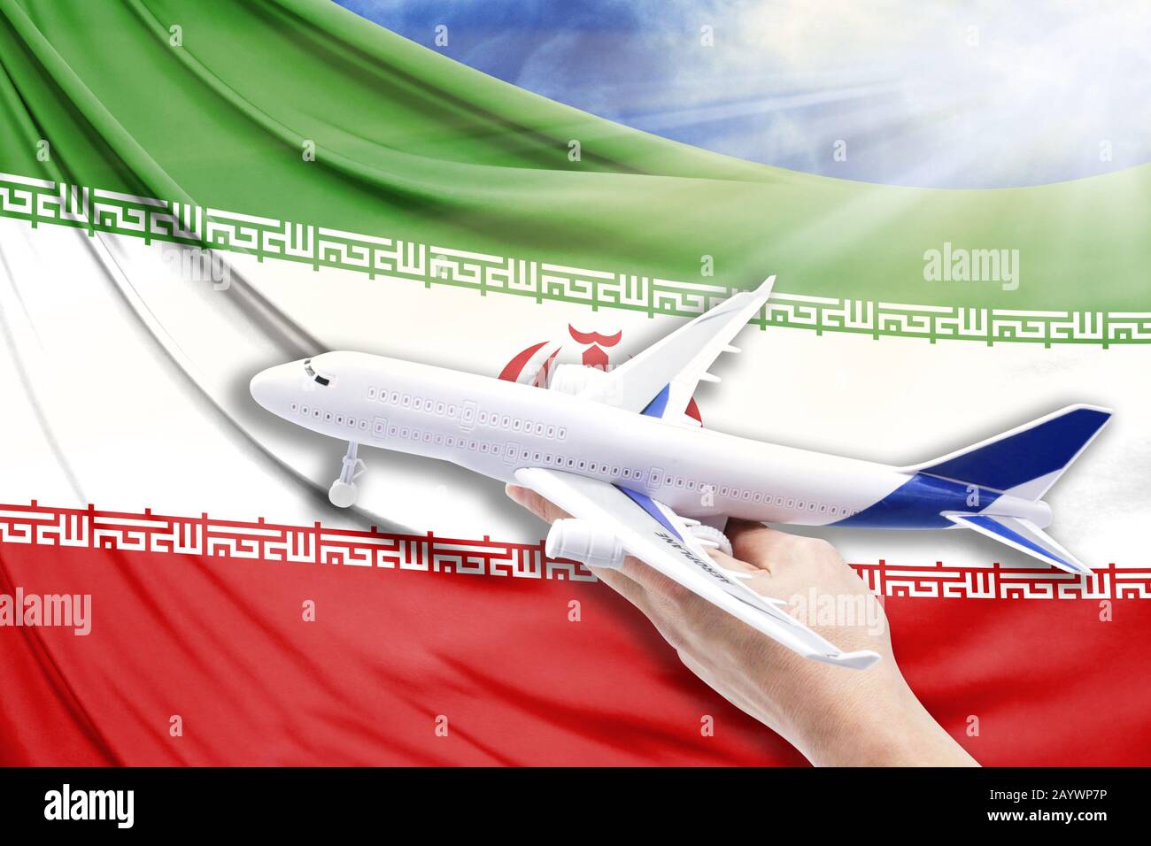 Airplane in hand with national flag of Iran on a background of blue sky ...