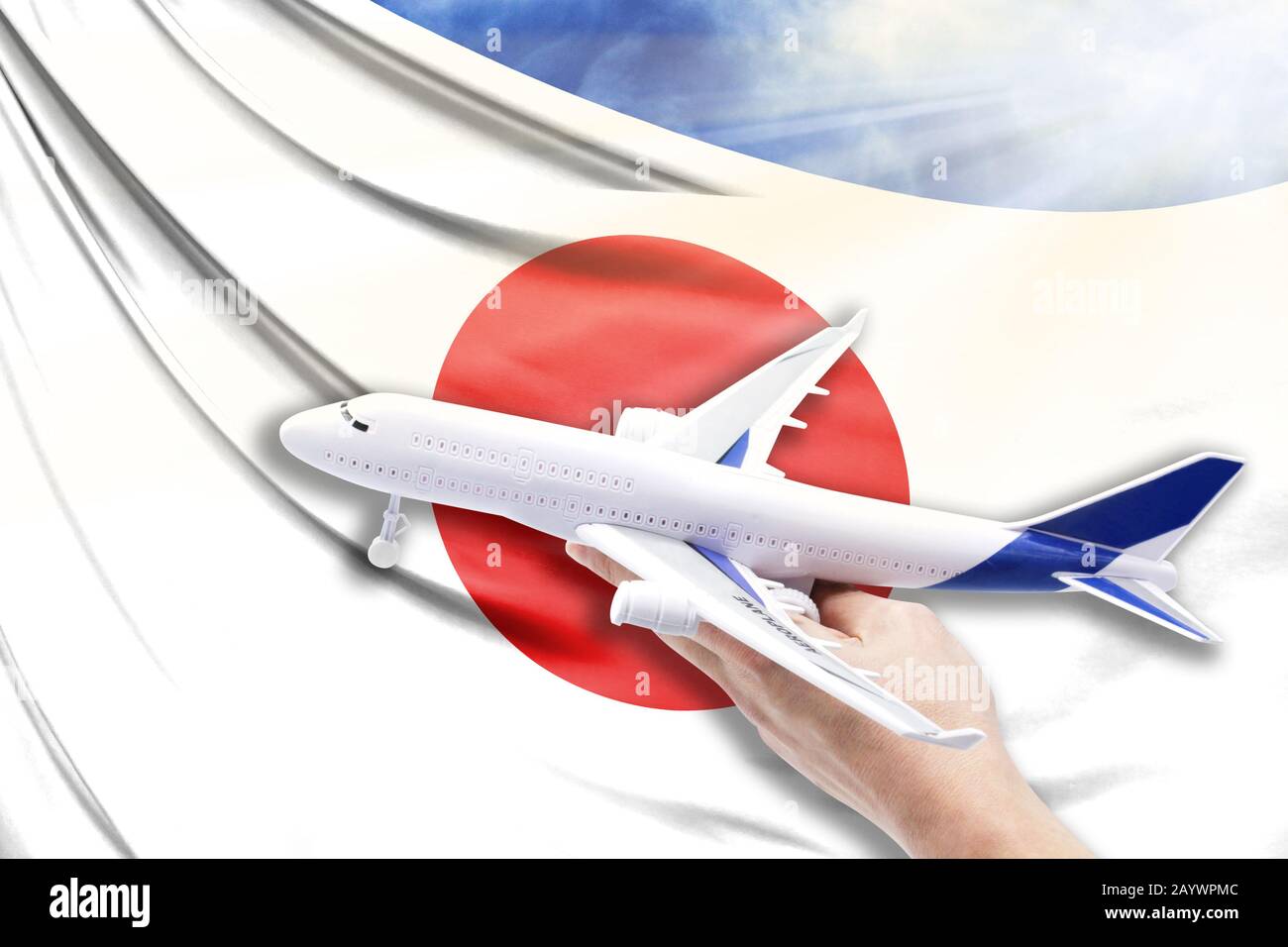 Airplane in hand with national flag of Japan on a background of blue ...
