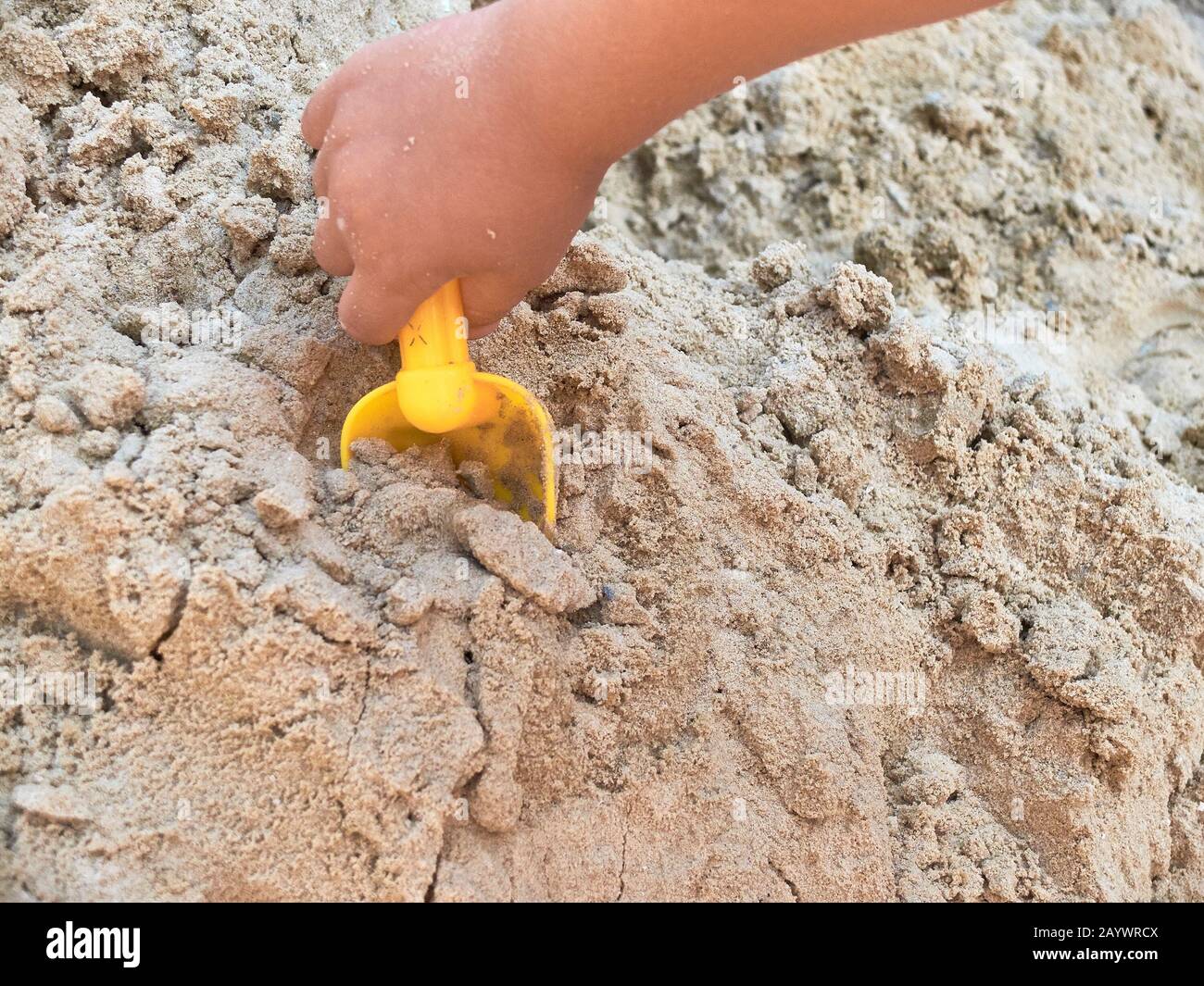 Hand of child playing in the sandbox with yellow scoop Stock Photo - Alamy