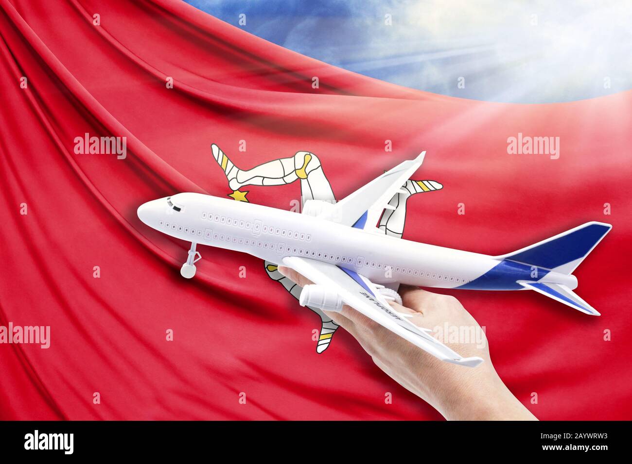 Airplane in hand with national flag of Isle Of Man on a background of ...