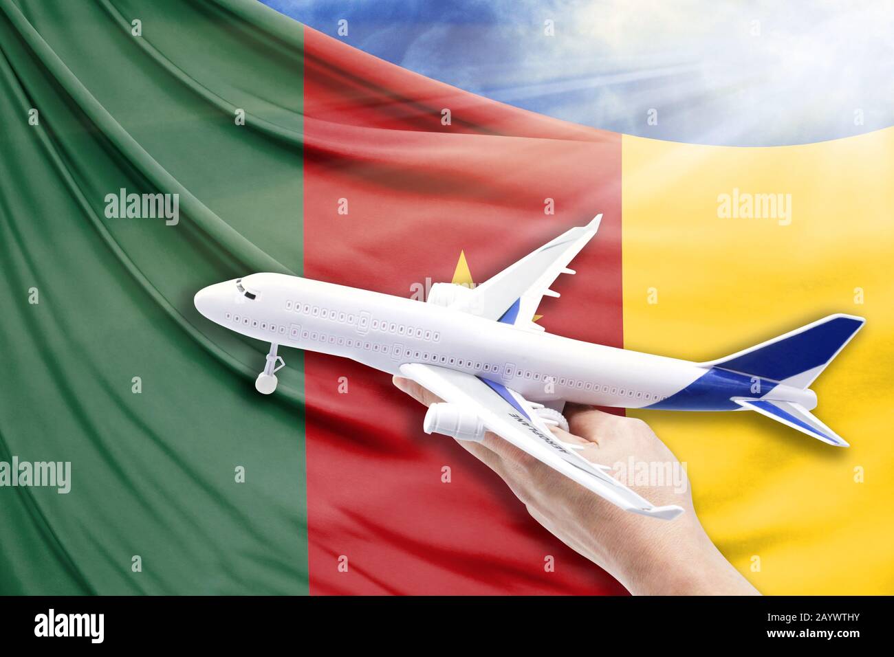 Airplane in hand with national flag of Cameroon on a background of blue ...