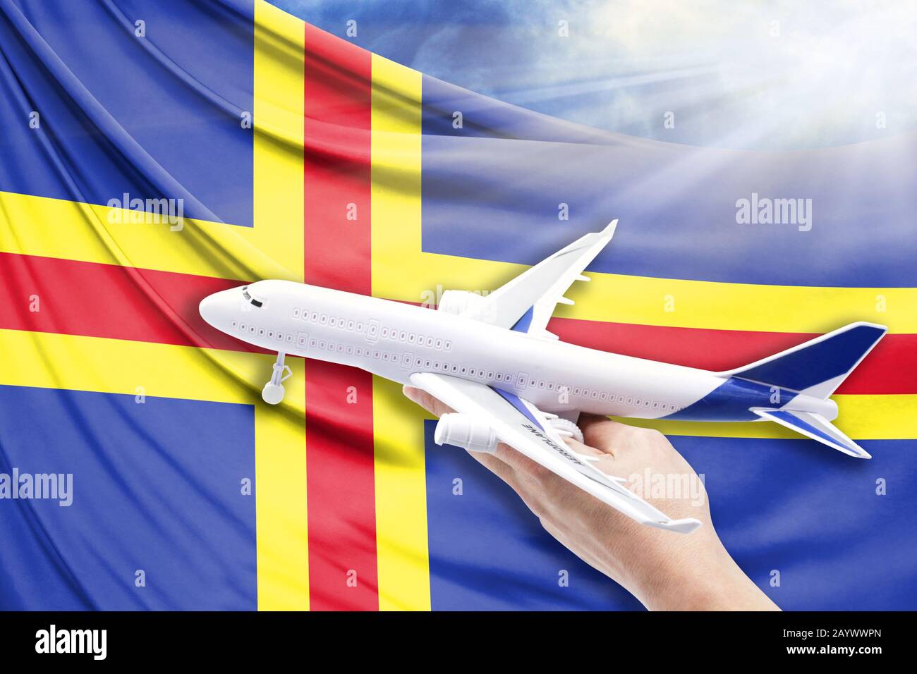 Airplane in hand with national flag of Aland on a background of blue ...