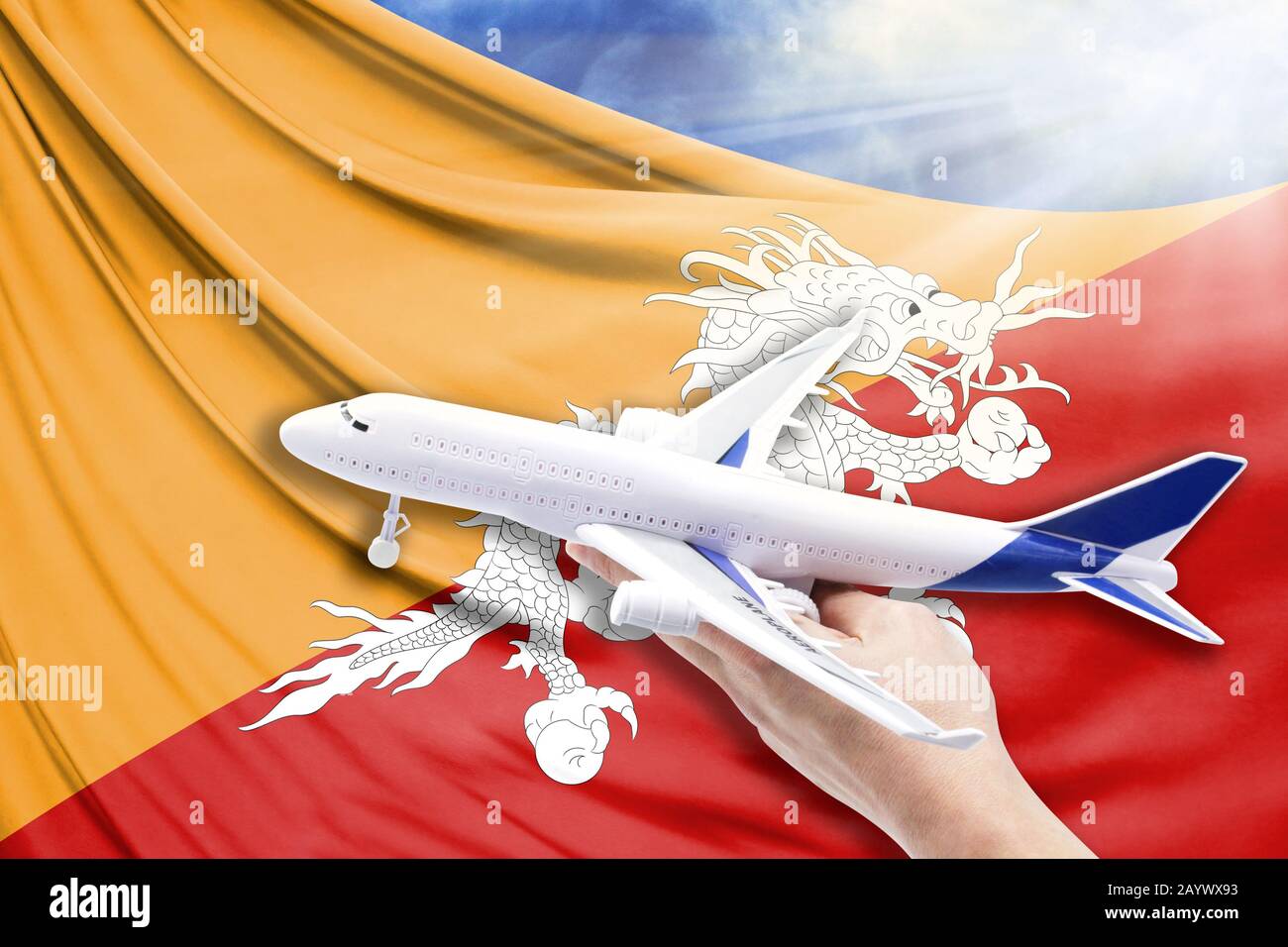 Airplane in hand with national flag of Butane on a background of blue ...
