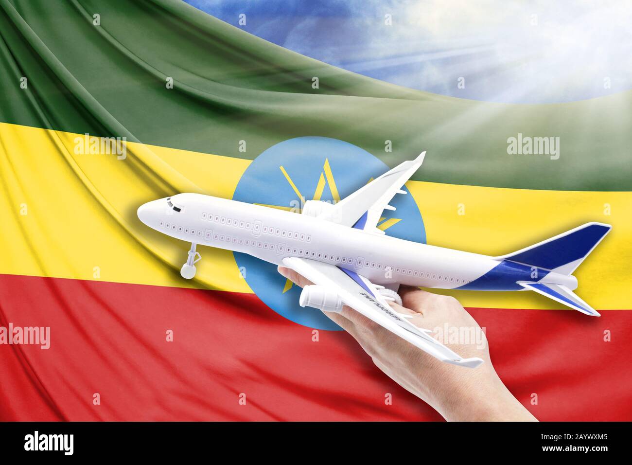 Airplane in hand with national flag of Ethiopia on a background of blue ...