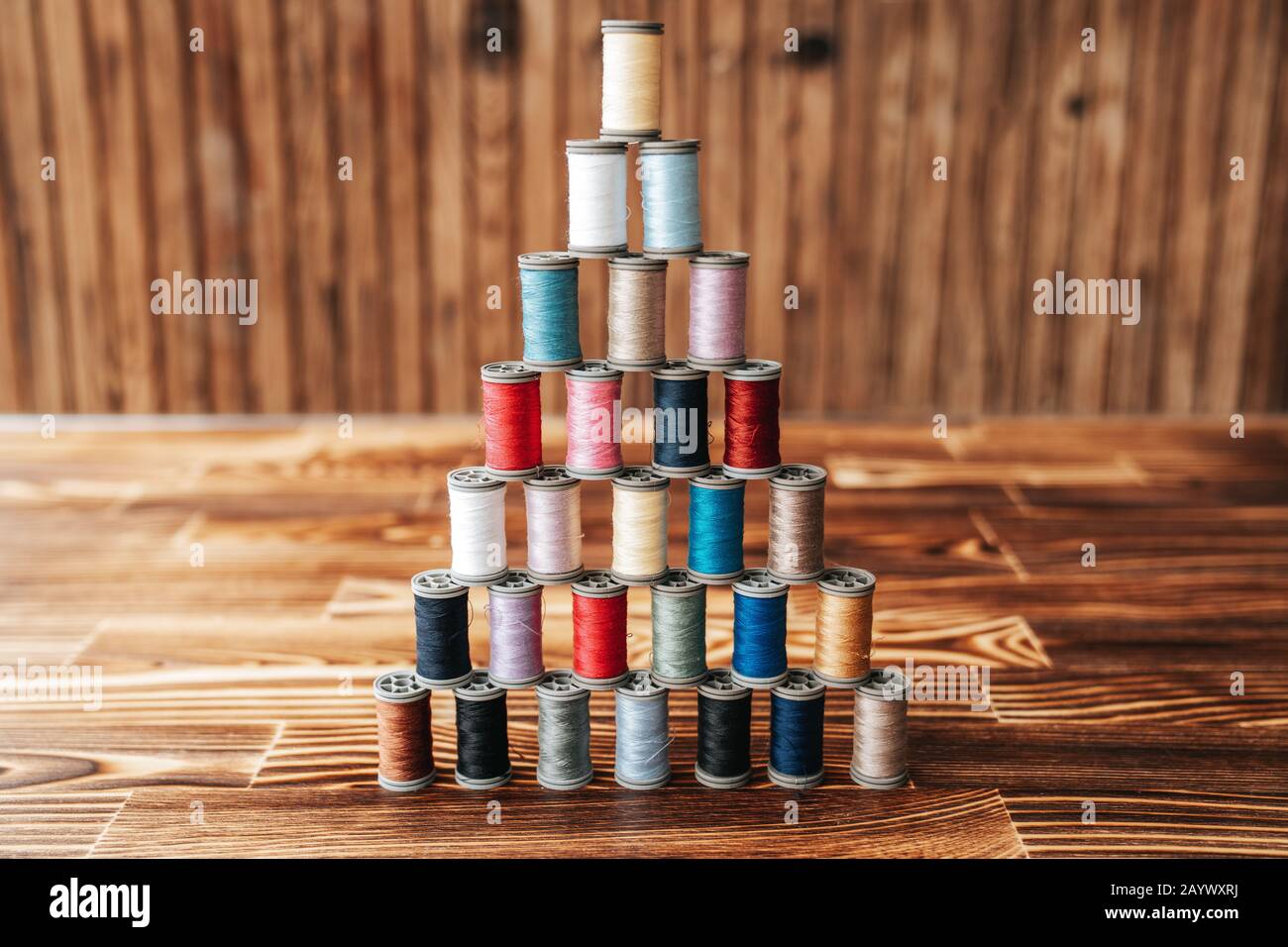 Many overlaped thread spools in a pyramid shape on a wooden background ...