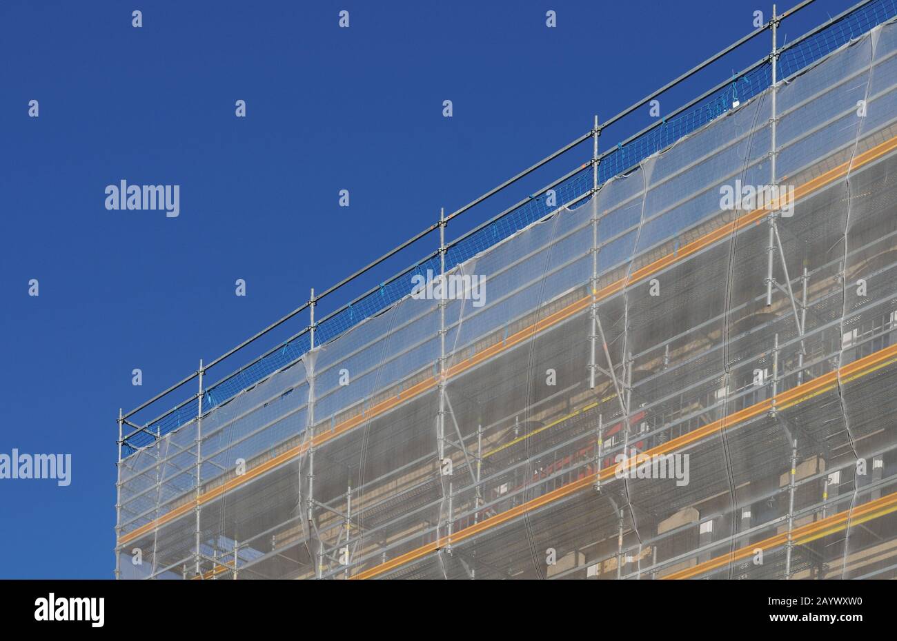 scaffold at a building under renovation covered with a white safety net ...