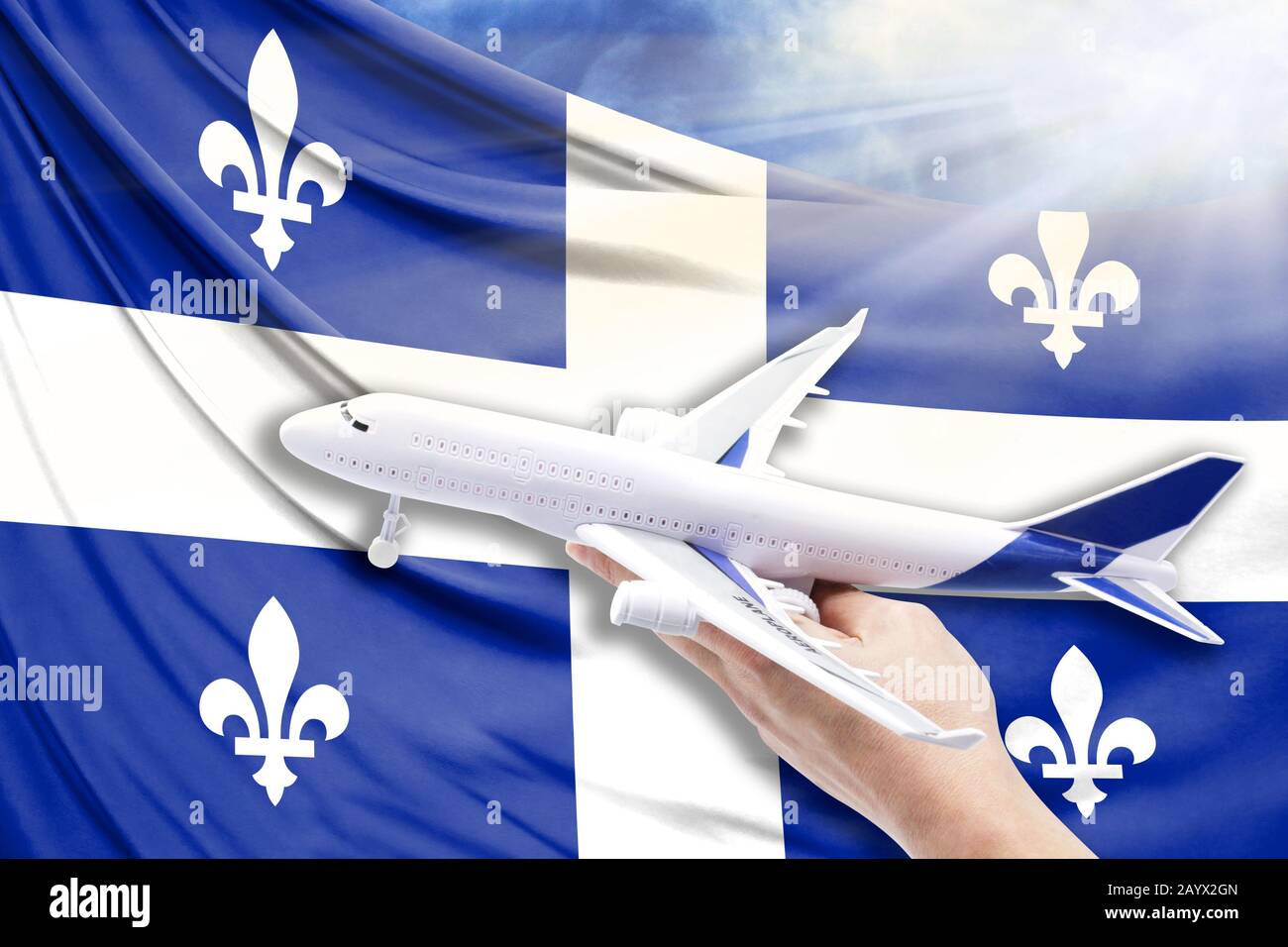 Airplane in hand with national flag of Quebec on a background of blue ...