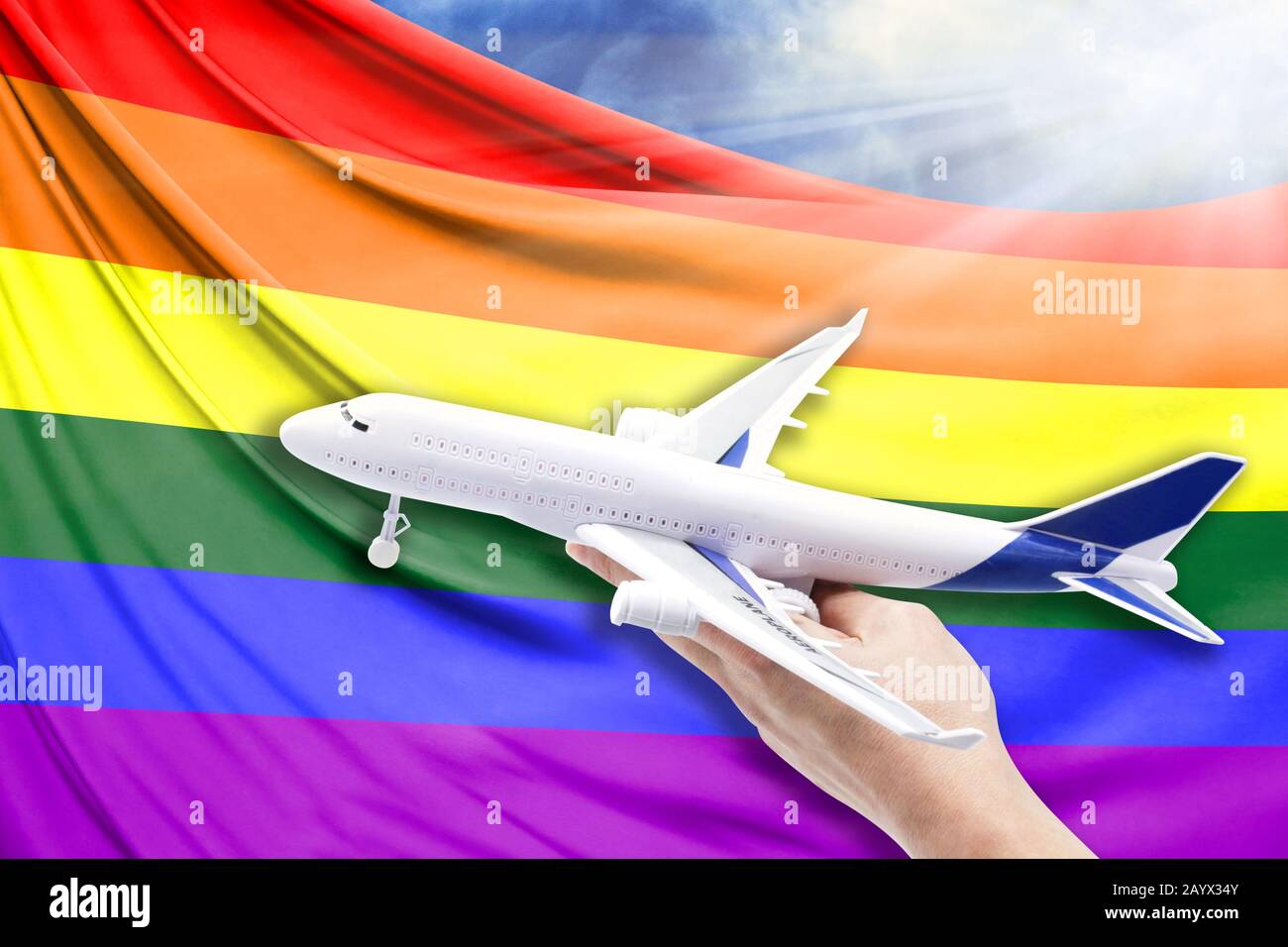 Airplane in hand with national flag of lgbt on a background of blue sky ...