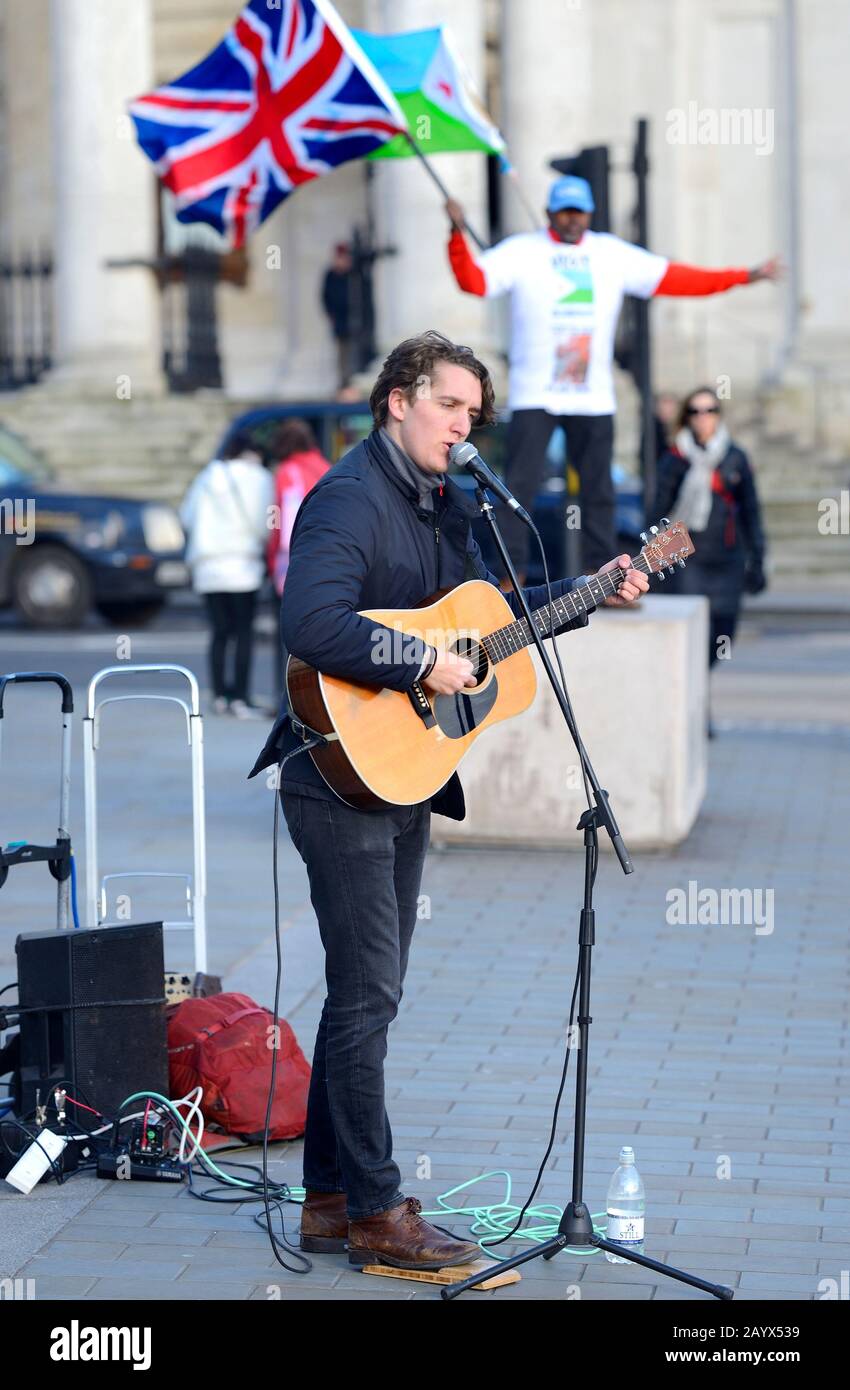 London, England, UK. Busker singing in Trafalgar Square with man waving ...