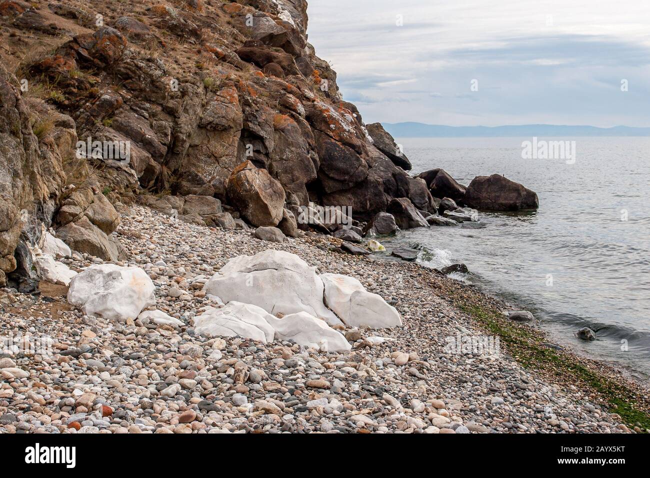 Large white marble stones by the lake next to the brown cliffs. The sky ...