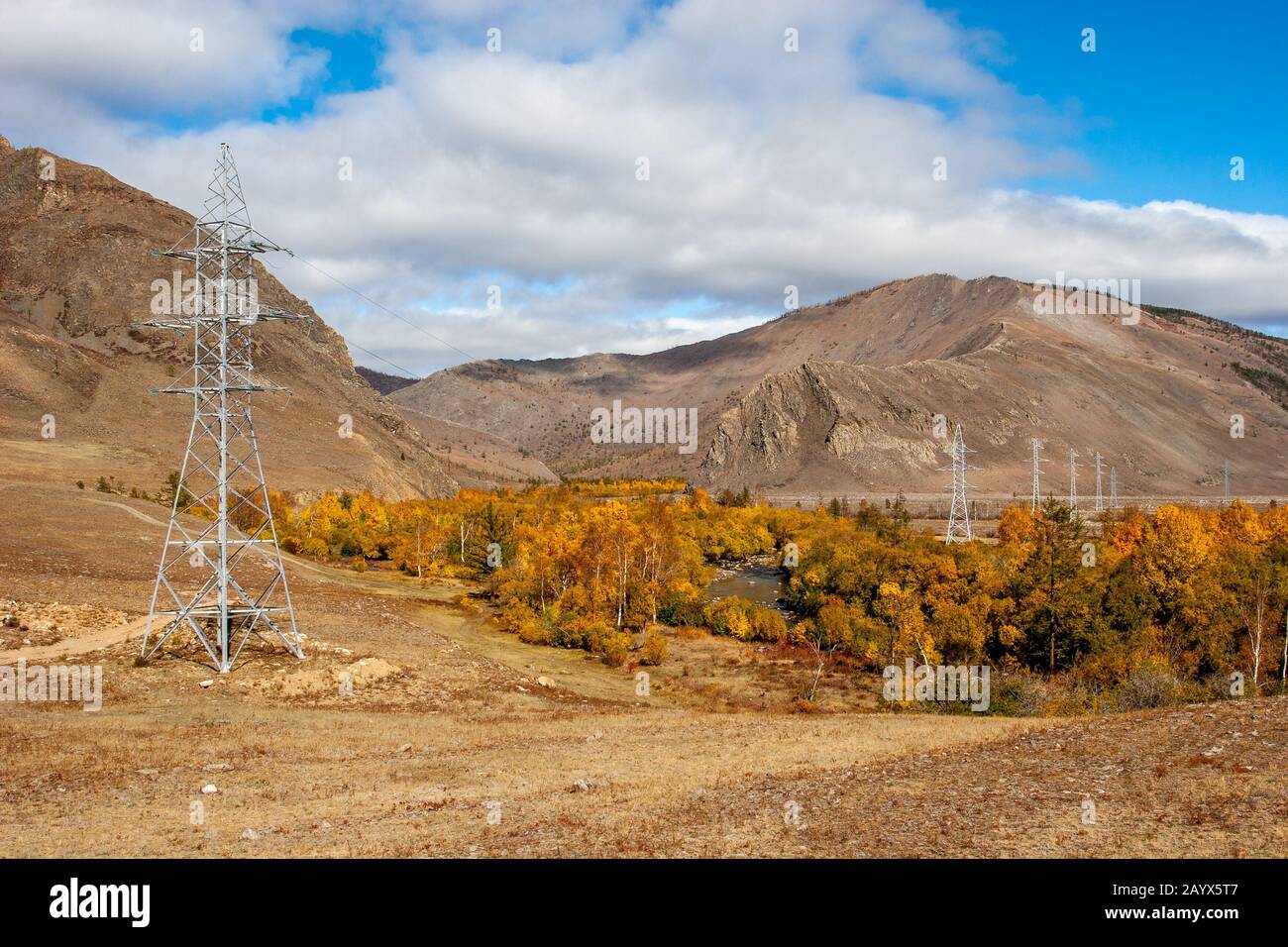 A river flows between mountains with yellow trees along the shore and ...