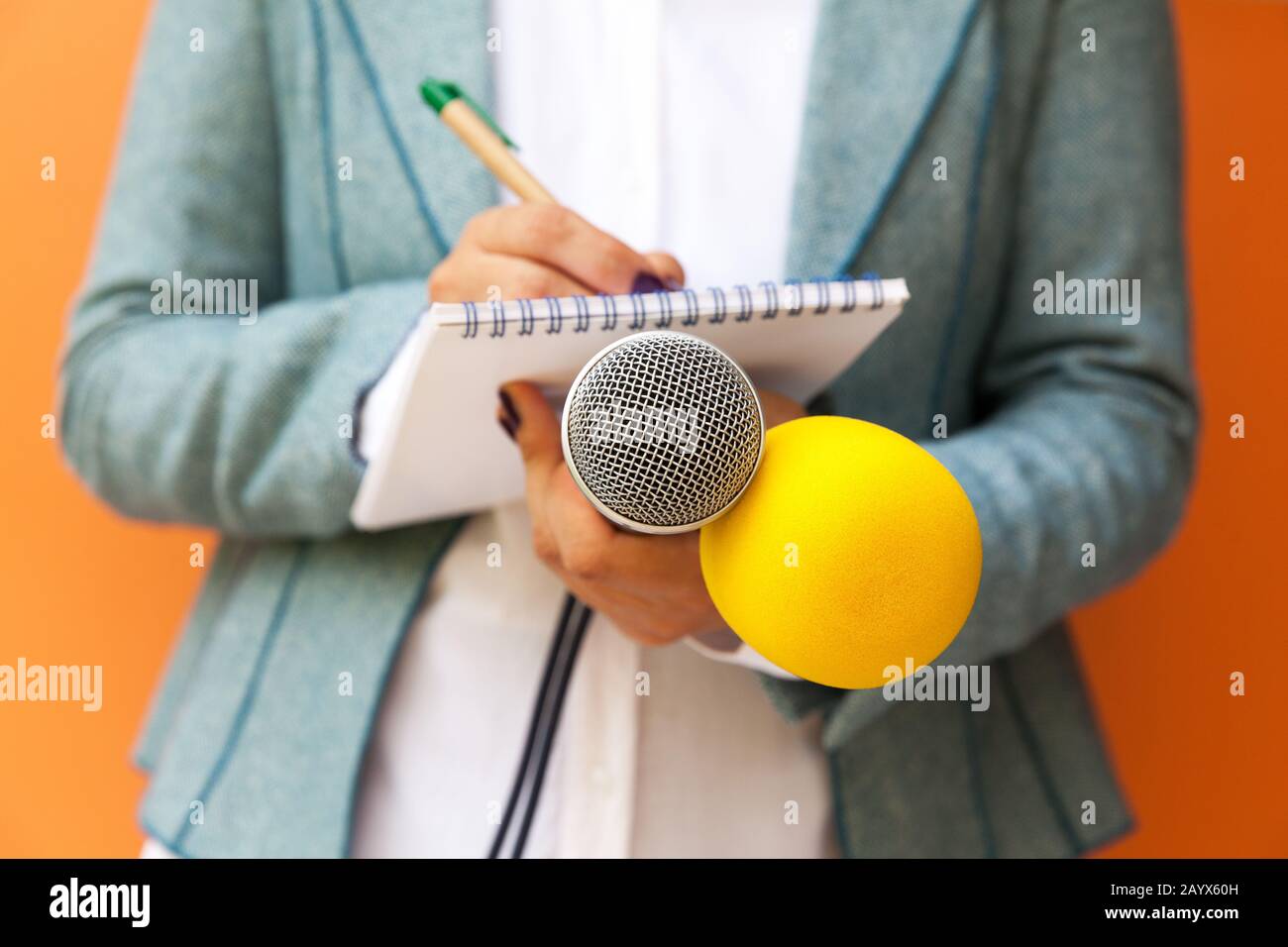Female reporter at press conference, writing notes, holding microphone ...