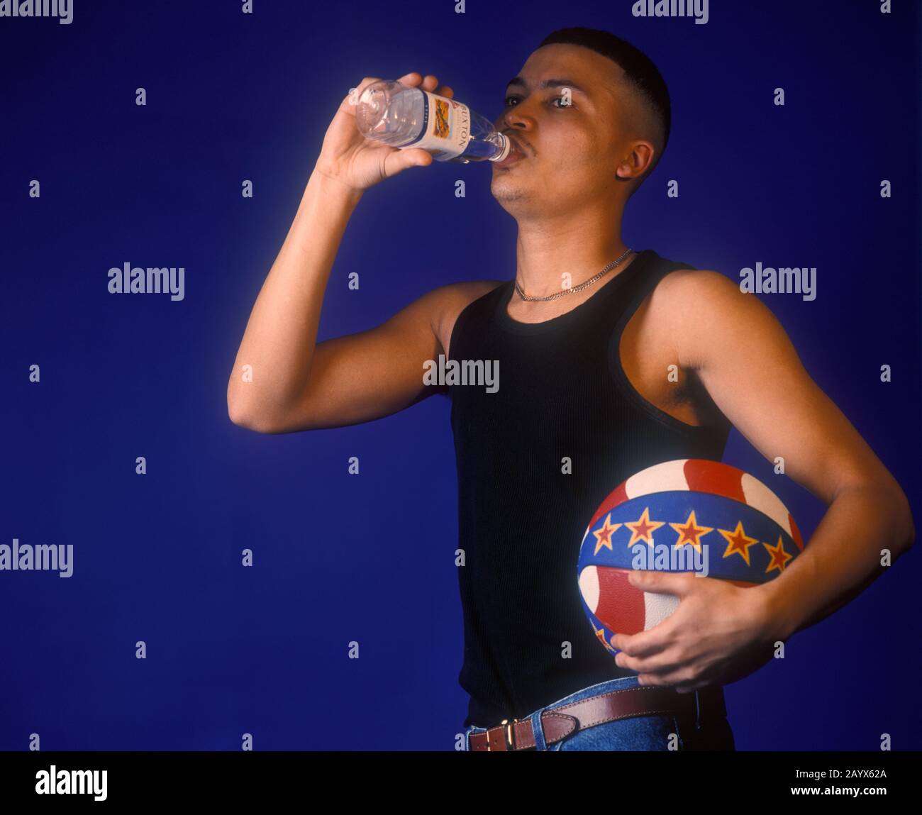 Teenage boy drinking water holding a basketball Stock Photo - Alamy