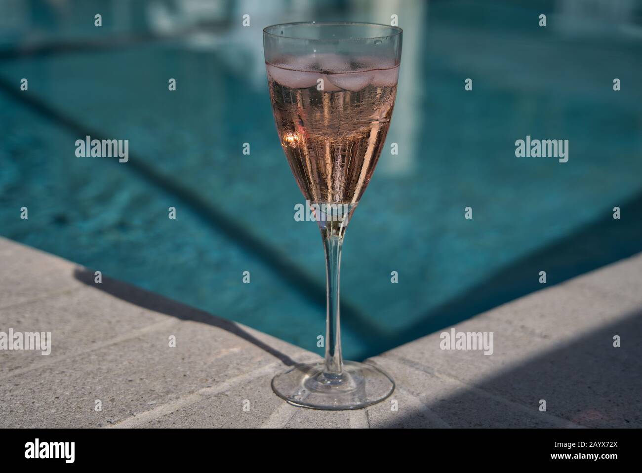 A glass of champagne sparkling wine by the pool with bokeh Stock Photo ...