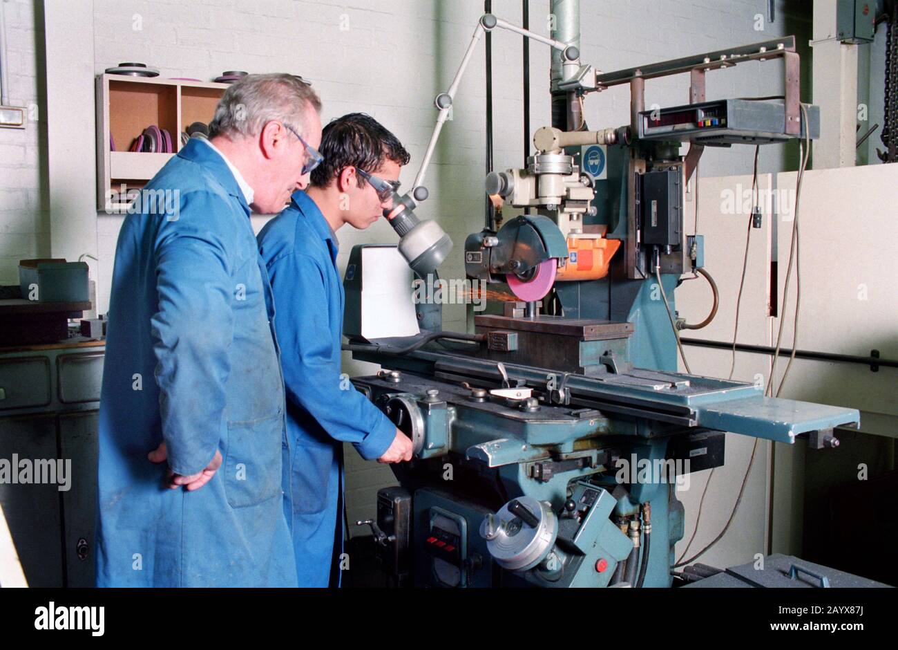 modern apprentice being shown how to use the surface grinding machine ...