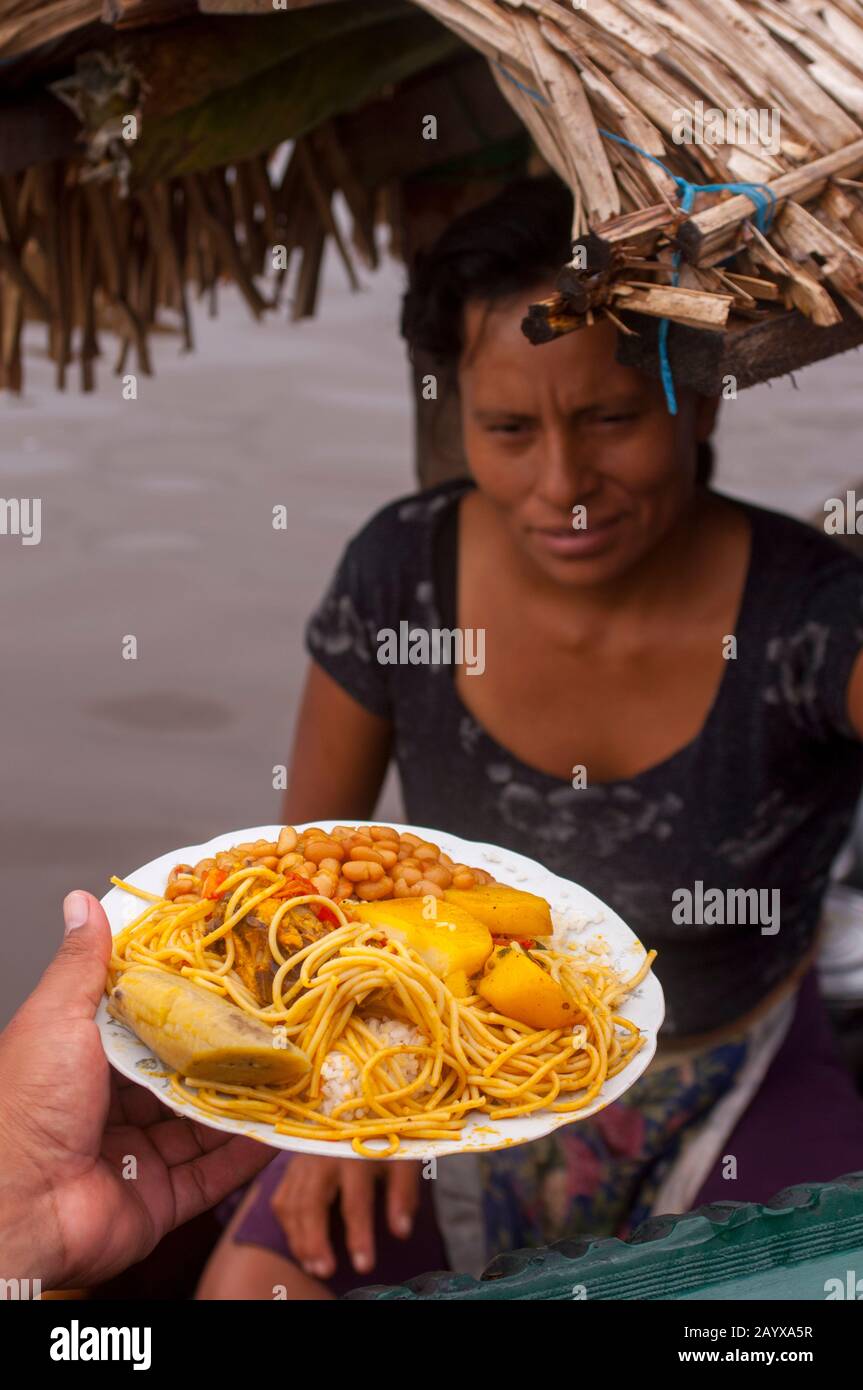 A woman is cooking food in her boat and selling it to people along the ...