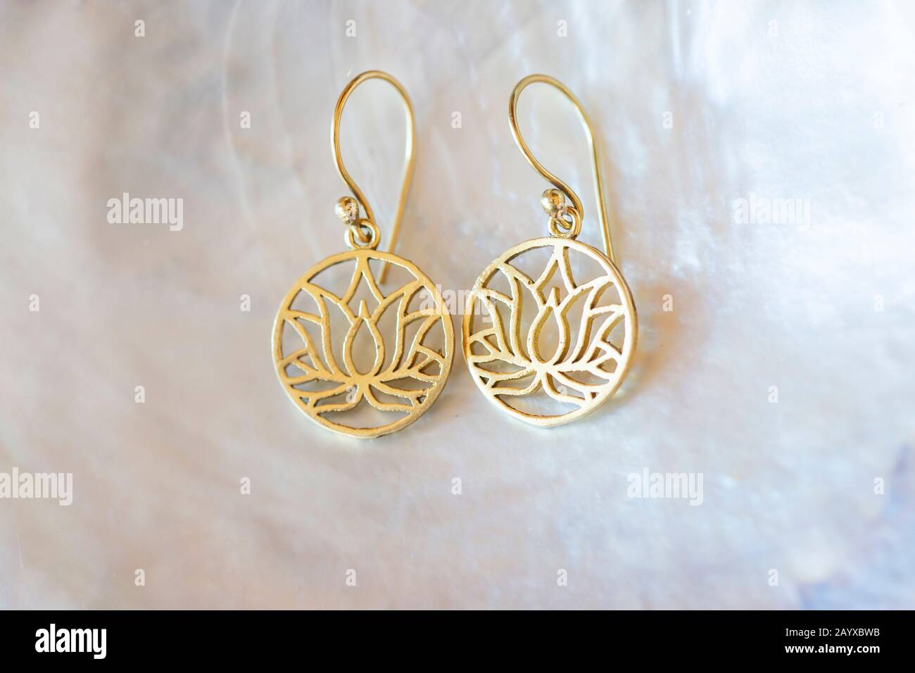 Brass earrings in lotus shape on shell background Stock Photo - Alamy