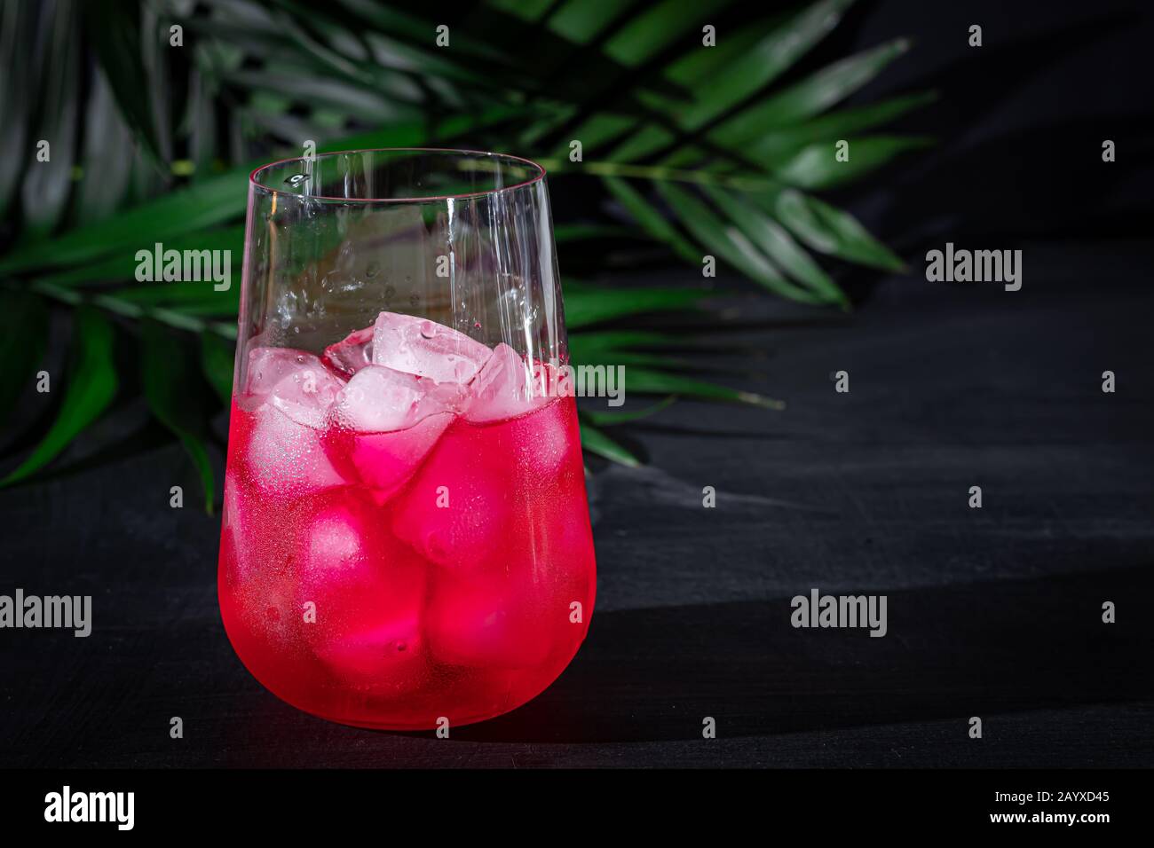 Raspberry-barberry drink in a transparent glass with ice. The drink is ...