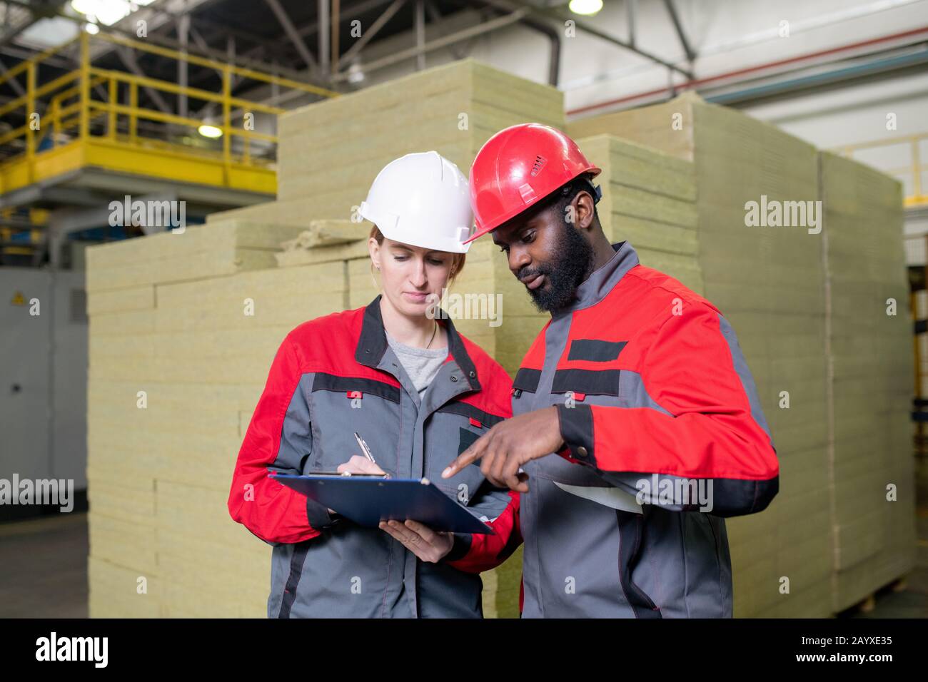 Horizontal medium portrait of male and female construction supplies factory workers making ...