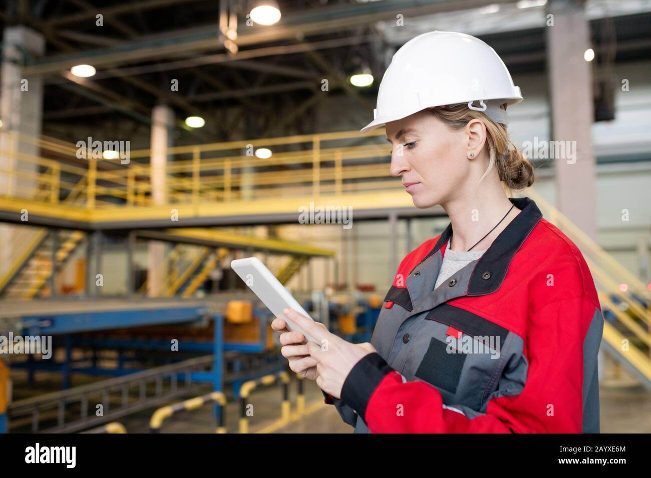 Horizontal portrait shot of professional female factory worker wearing ...