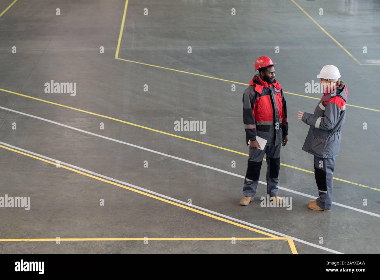 Horizontal high angle long shot of two young adult factory workers ...