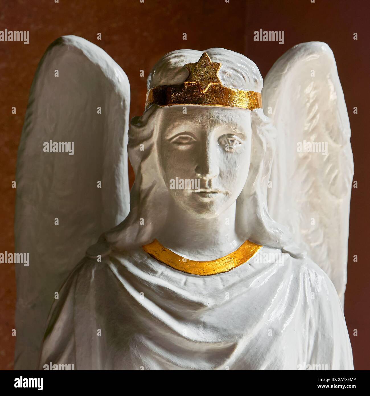 A white painted statue of an angel with golden star, holding a shell ...