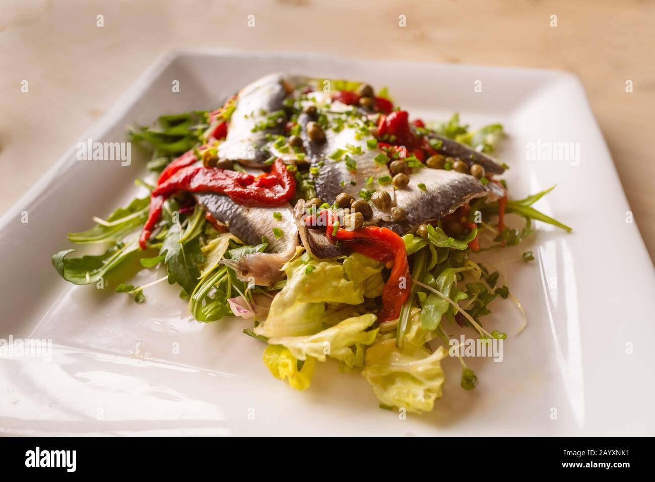 Cured mackerel fillets and pickled pepper salad on a square with plate ...