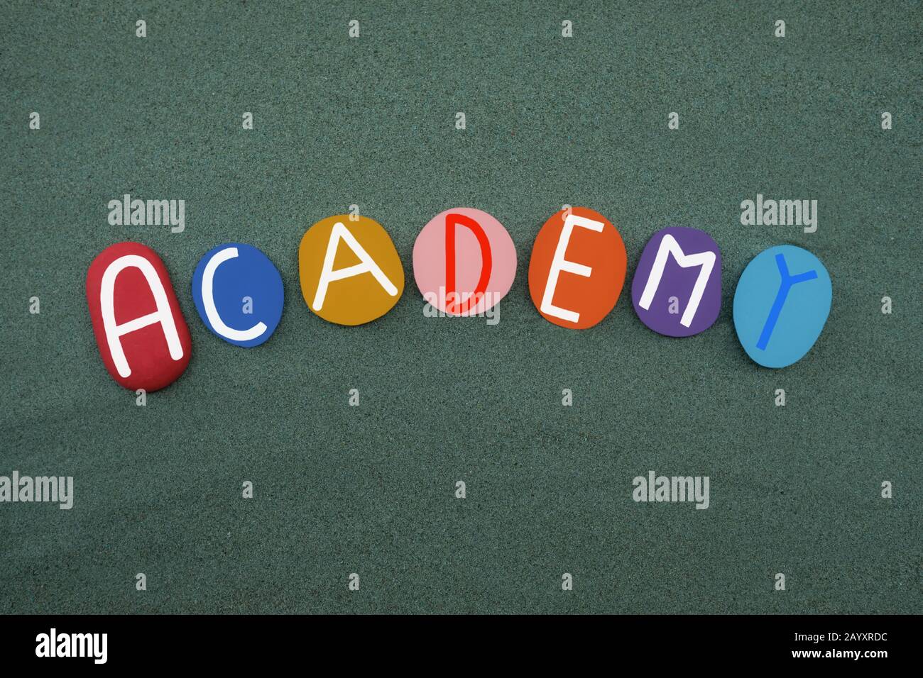Academy word composed with multi colored stone letters over green sand ...