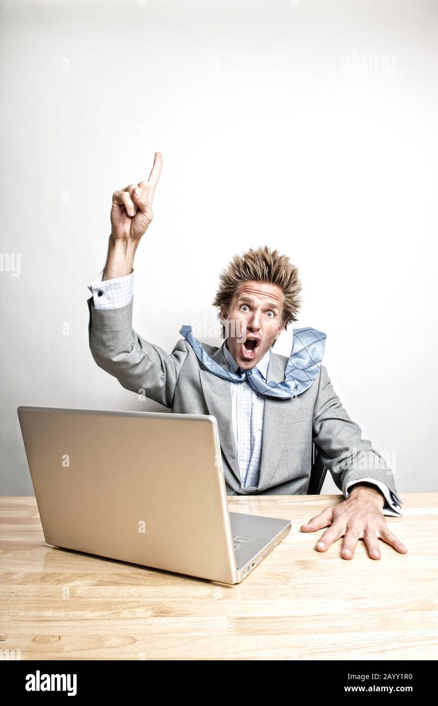 Businessman celebrating in front of his laptop computer raising his ...