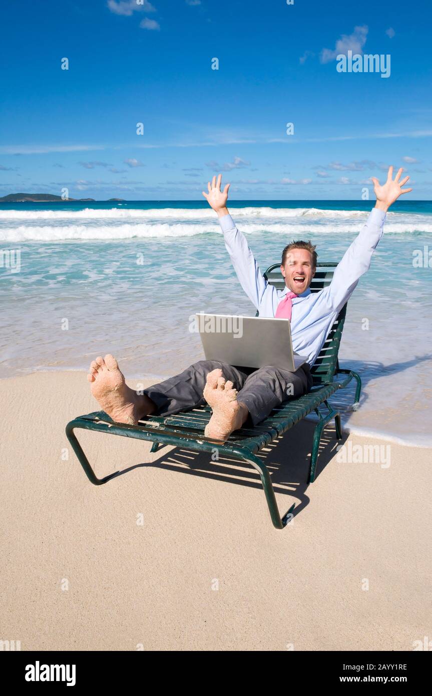 Excited barefoot businessman celebrating outdoors with his computer on ...