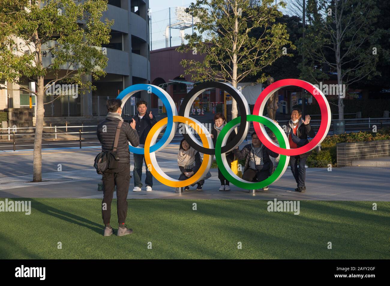 A man takes a photo of people posing behind the Olympic Rings near the ...